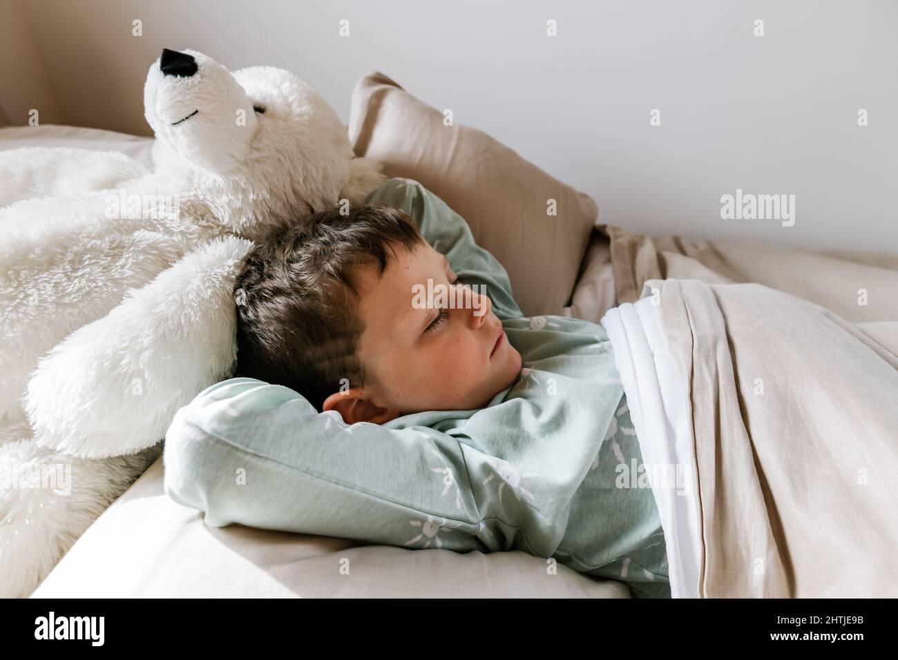 Side view of boy in pajama eyes closed while lying down on comfortable ...