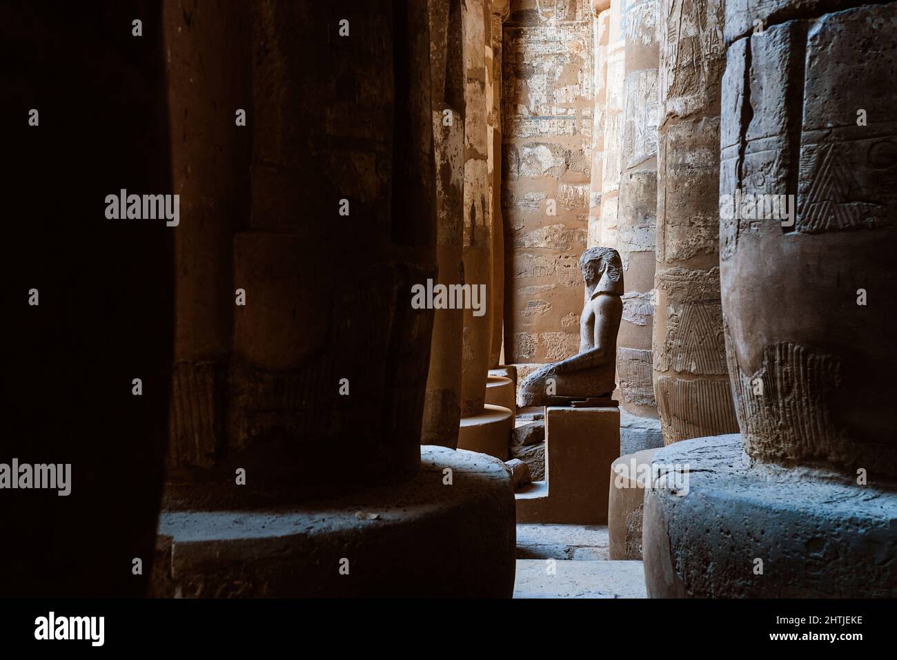 Ancient pharaoh statue placed on stand near shabby high columns with ...
