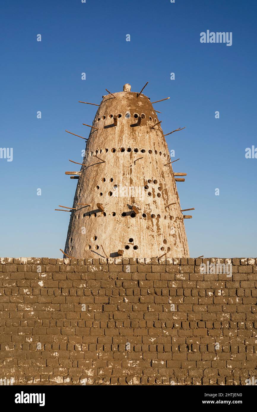 High conical Egyptian bird nesting tower with holes and wooden sticks ...