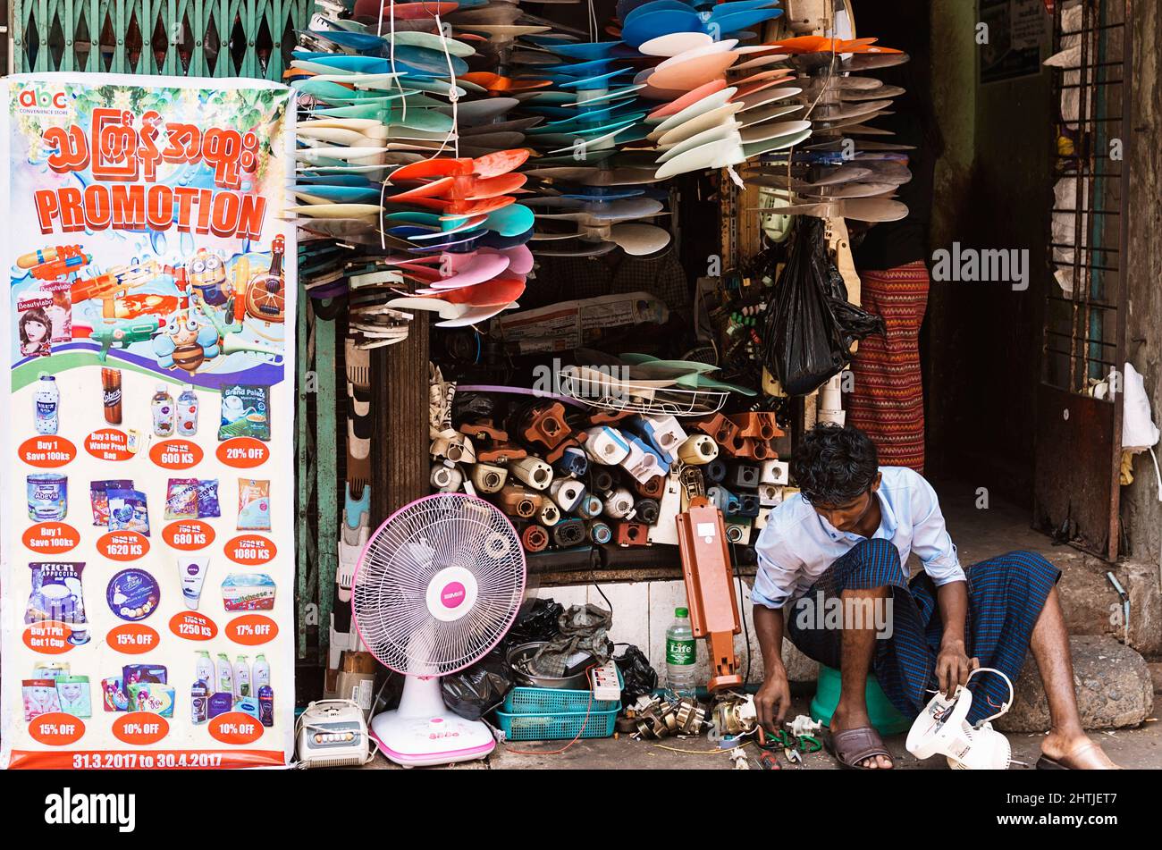 MYANMAR - APRIL 10, 2017: Indigenous Myanmarese man sitting on street and selling second hand ...