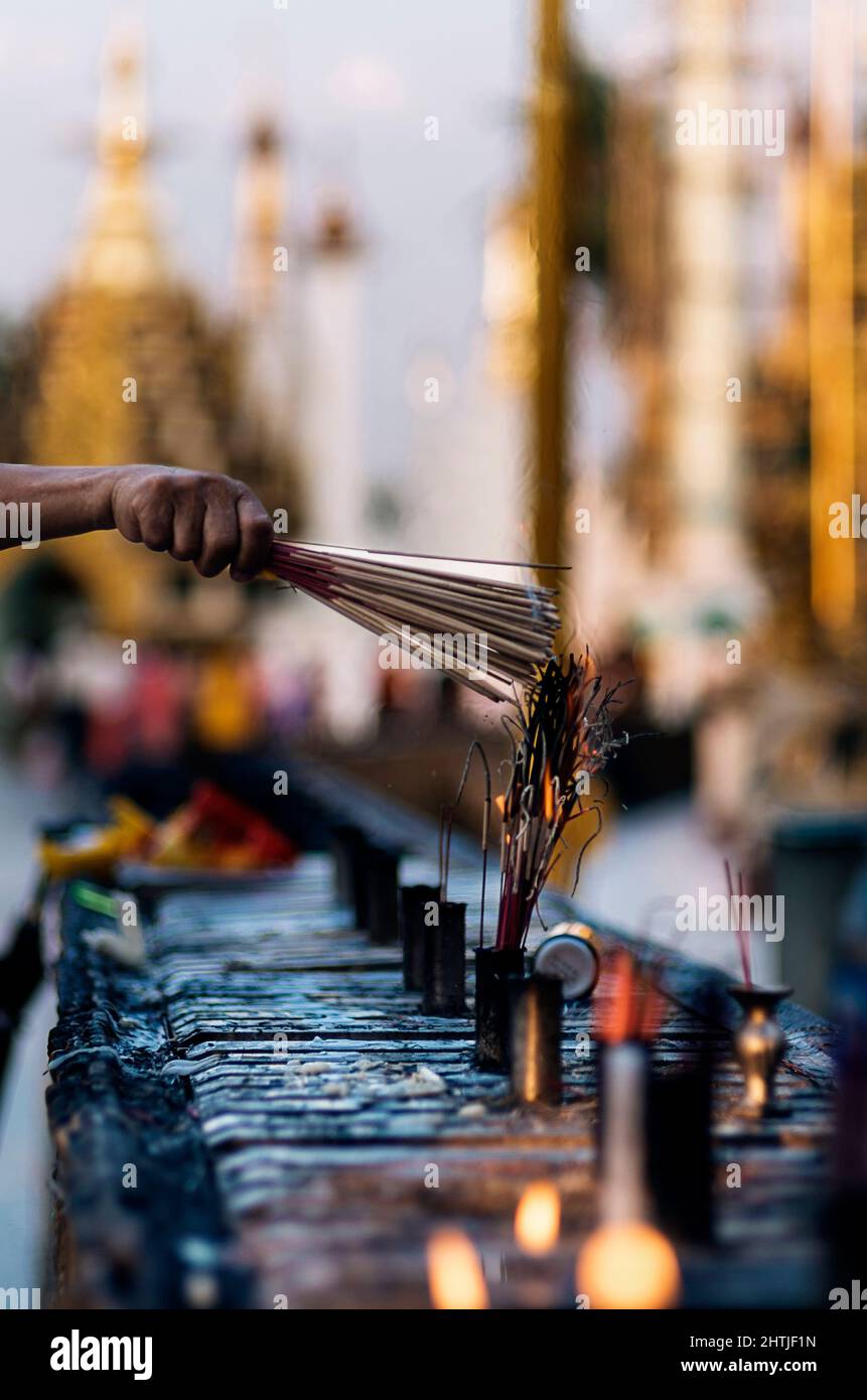 Hand of crop anonymous person burning incense sticks while standing ...