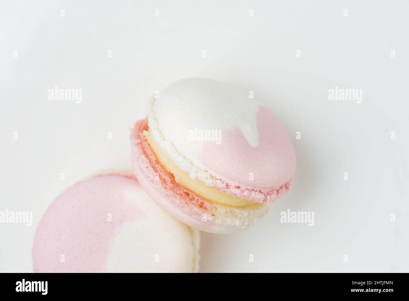 Sweet round pink and white macaroons with filling served on white ...