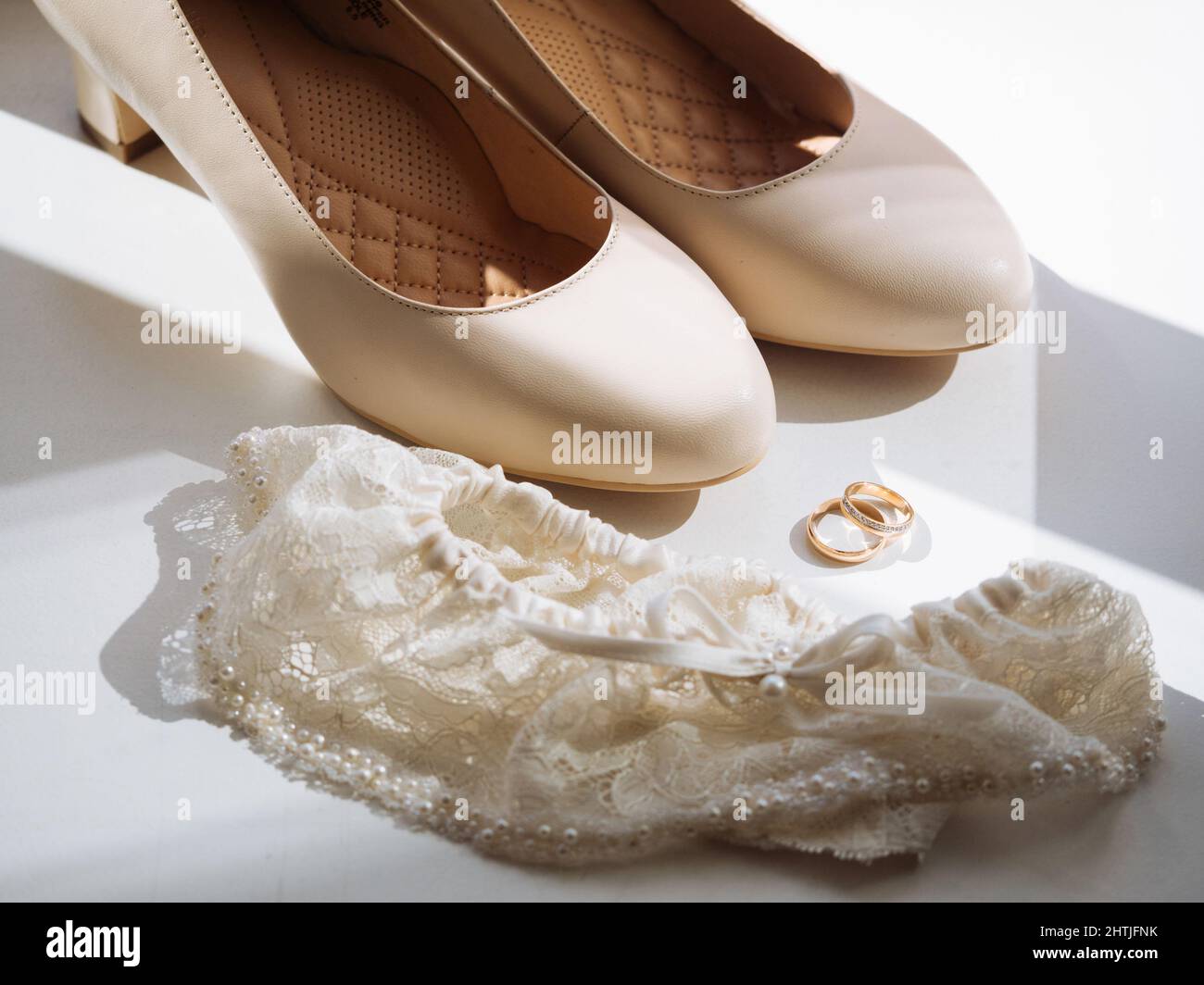 From above pair of wedding rings placed against elegant beige shoes and ...