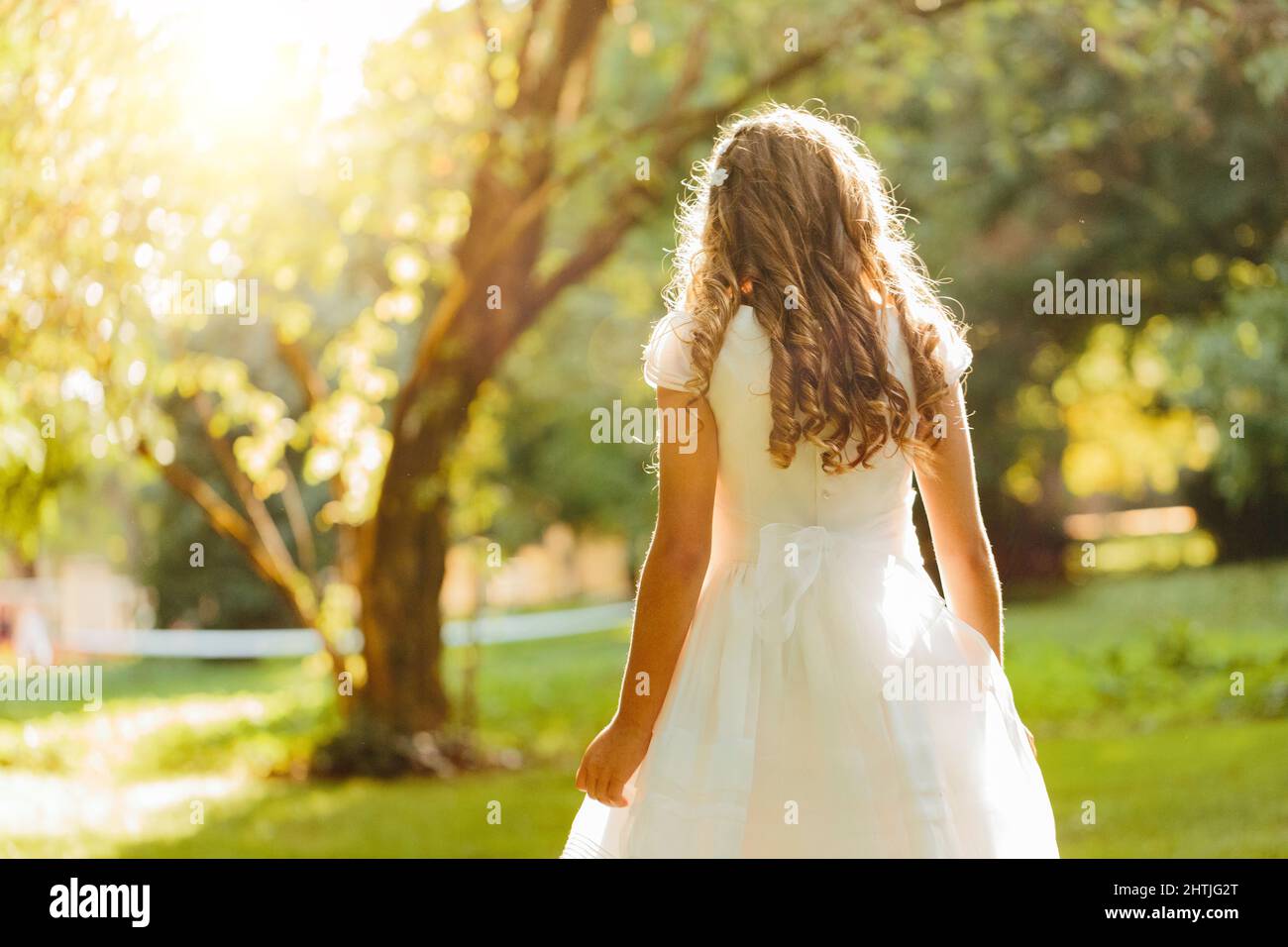 Back view of unrecognizable female in First Communion dress standing in ...