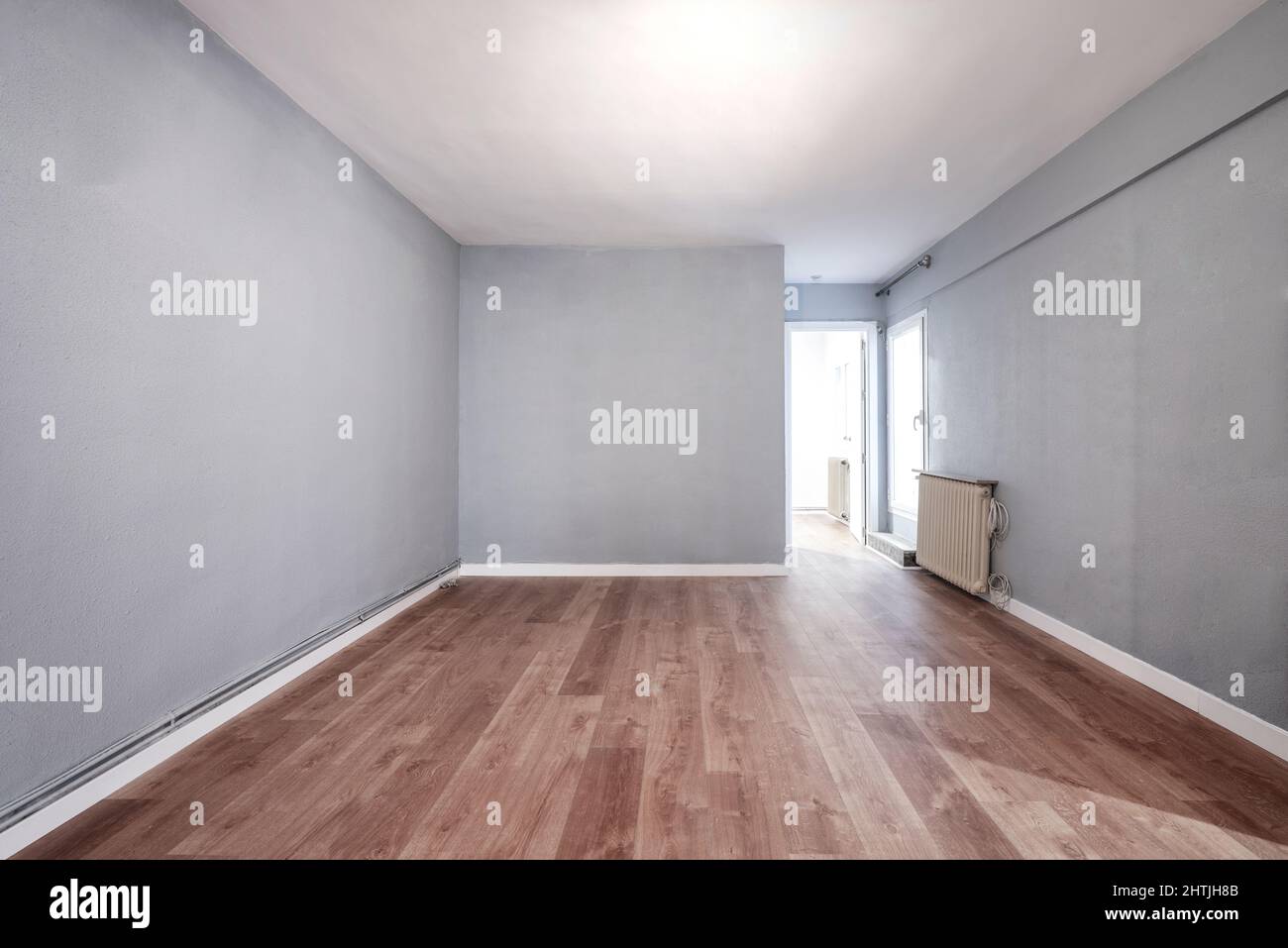 Empty room with cast iron radiator, white woodwork, gray painted walls ...