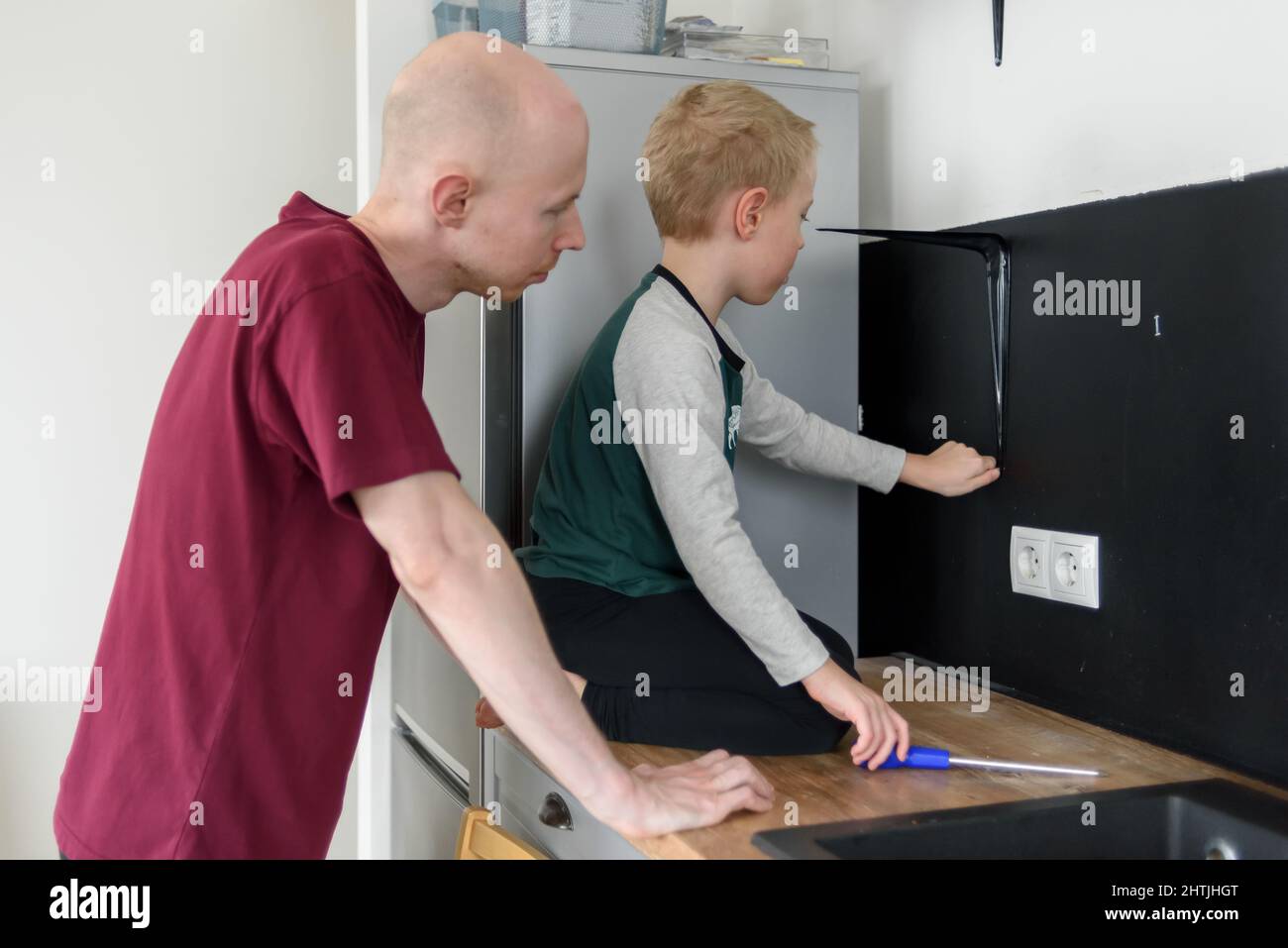 Father and son doing house renovations together. Using screwdriver. Dad ...