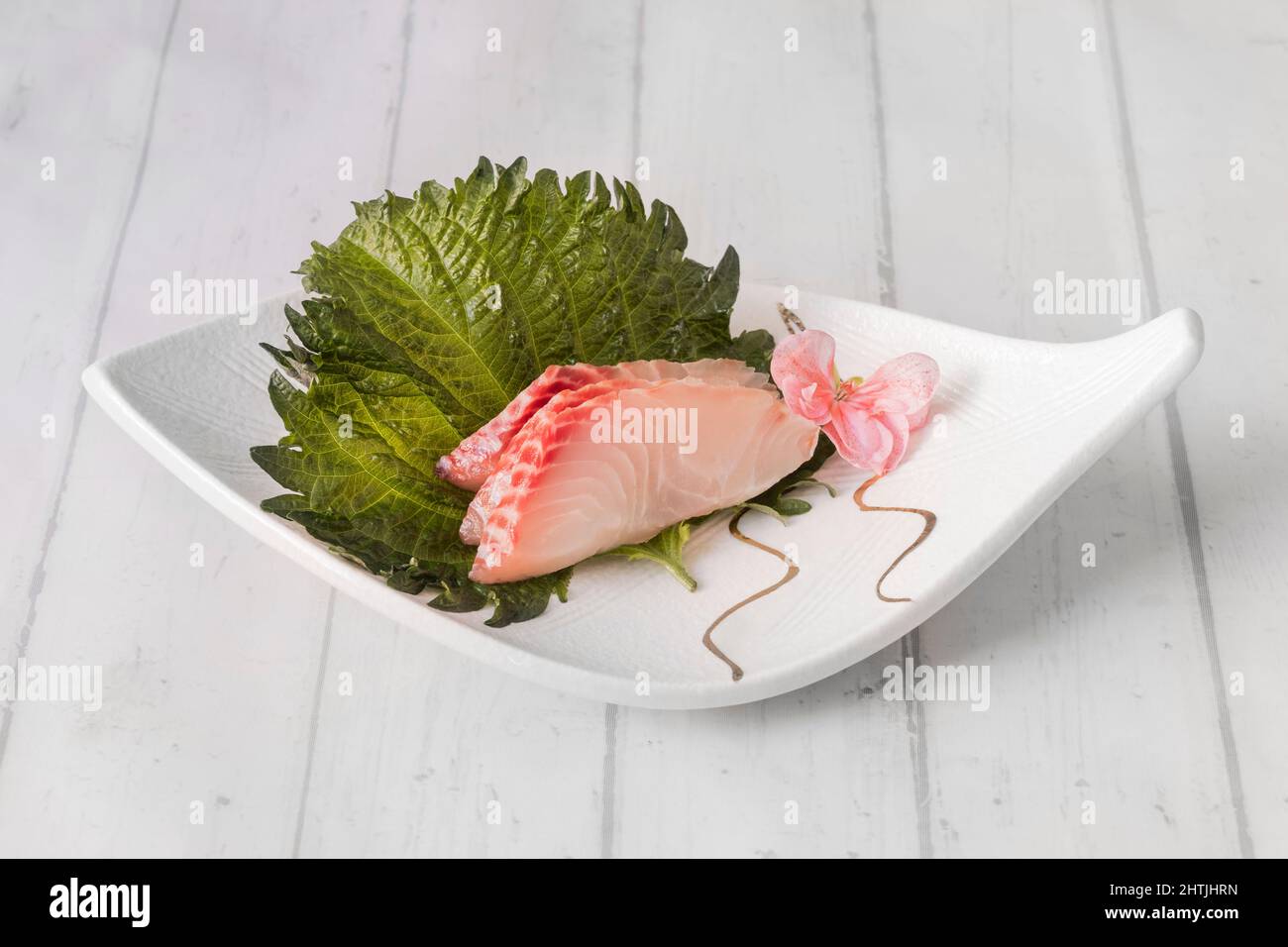 Pieces of sea bream sashimi on shiso leaf and white porcelain plate ...