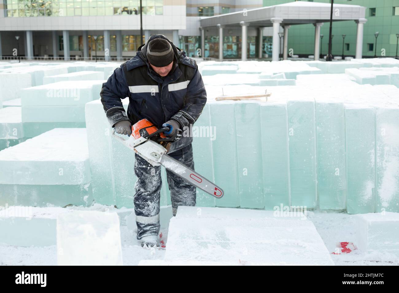 Construction worker saws an ice plate with a chainsaw Stock Photo - Alamy