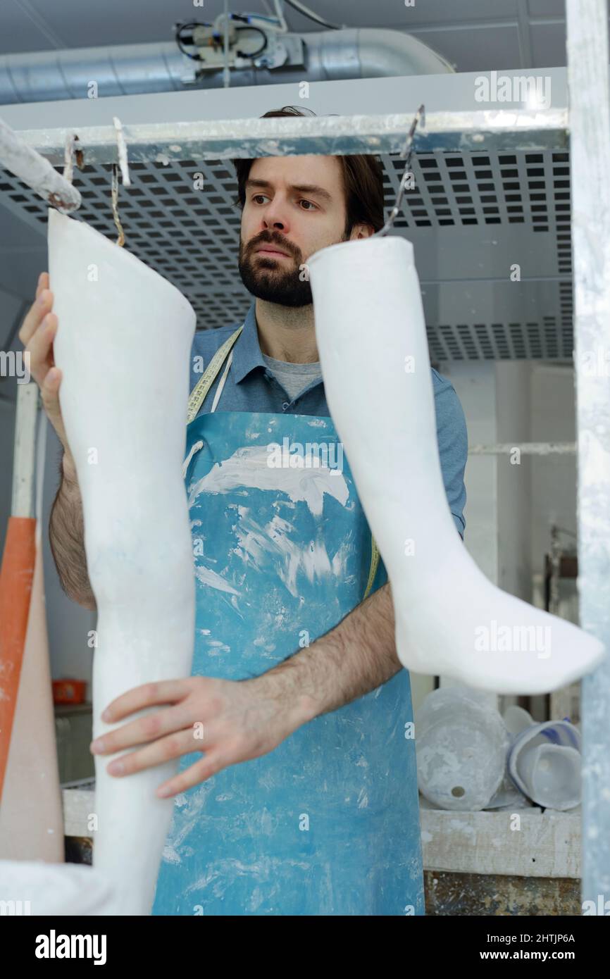 Young bearded male specialist of prosthetic factory in apron hanging ...