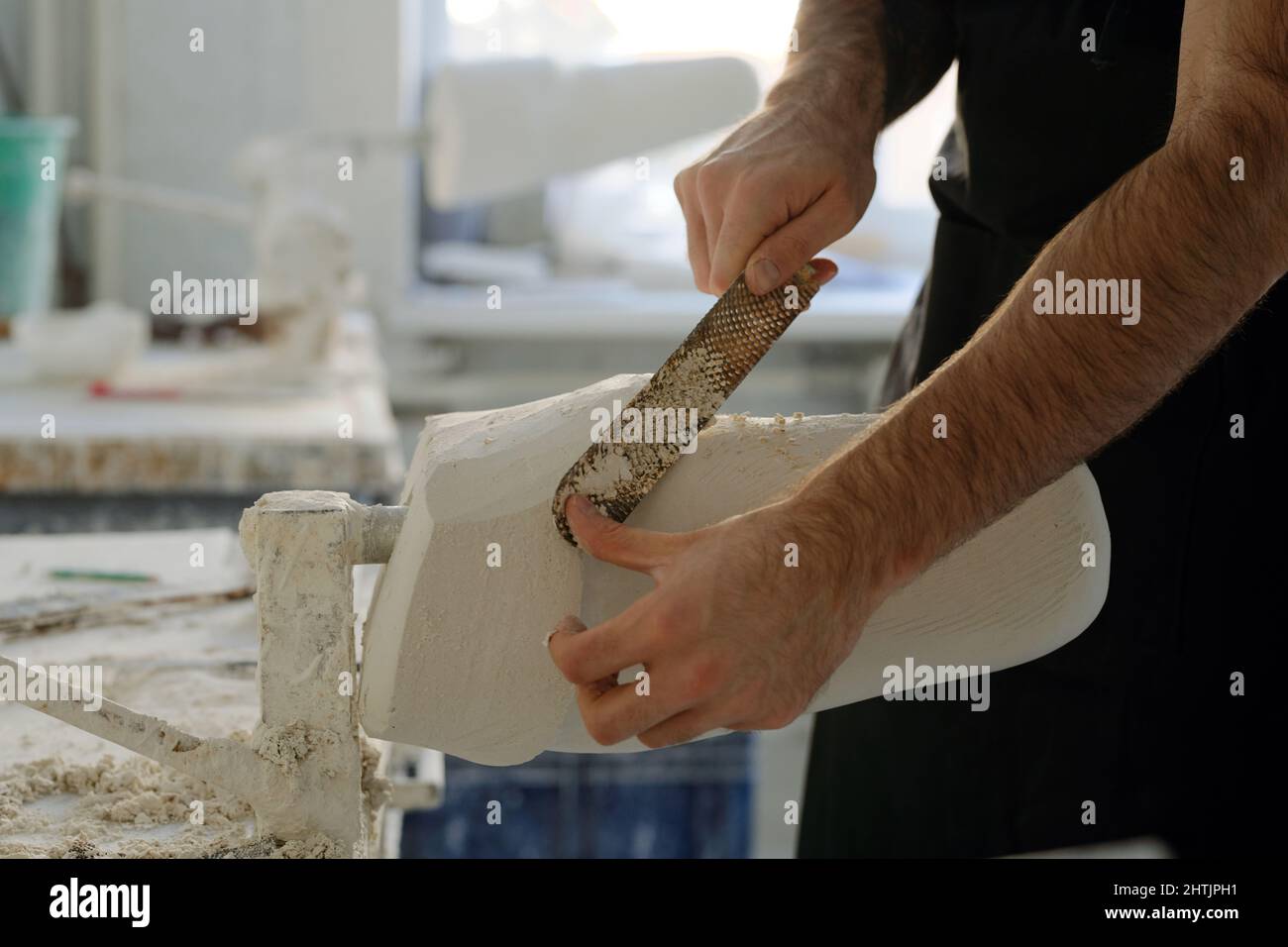 Hands of young factory worker with handtool removing excessive plaster ...