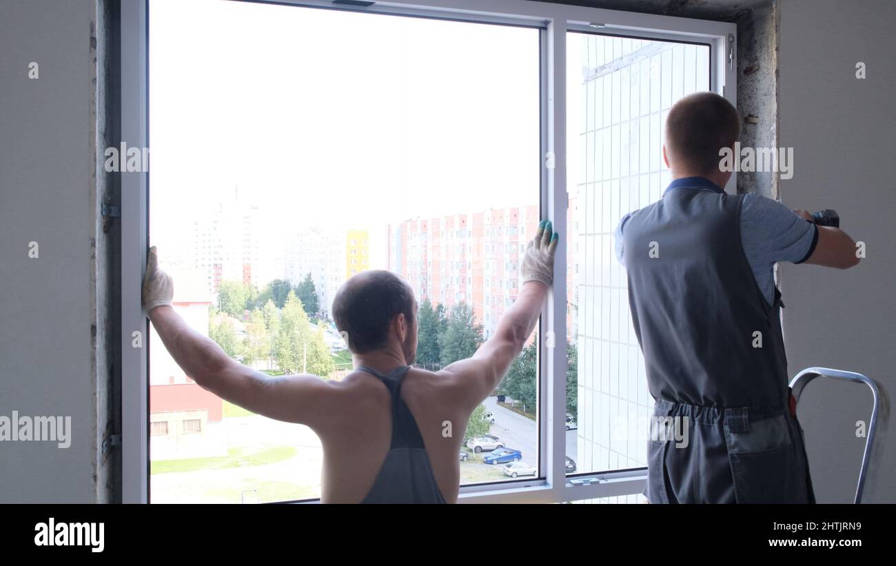 Dismantling and installation of a window in an apartment by two workers ...