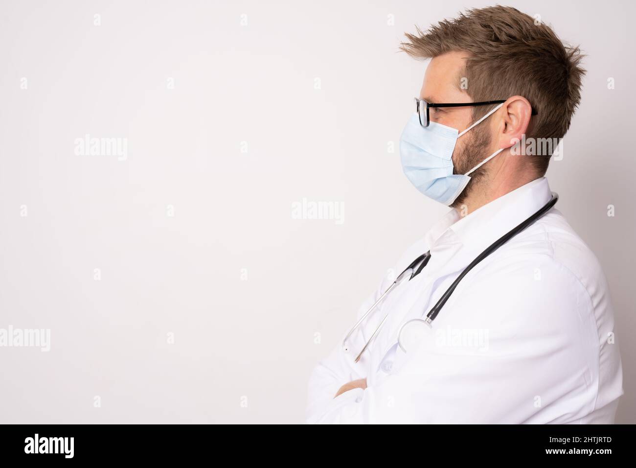 Side view of young male doctor posing with arms folded isolated on ...