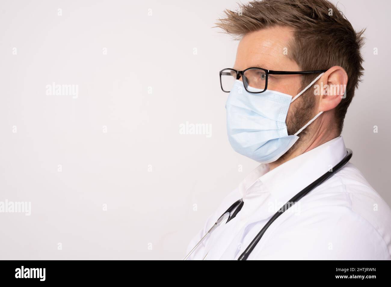 Side view of young male doctor posing with arms folded isolated on ...