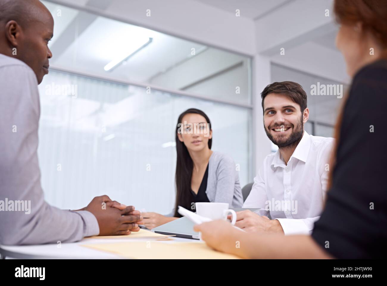 All smiles in the morning meeting. A group of coworkers sitting in an ...