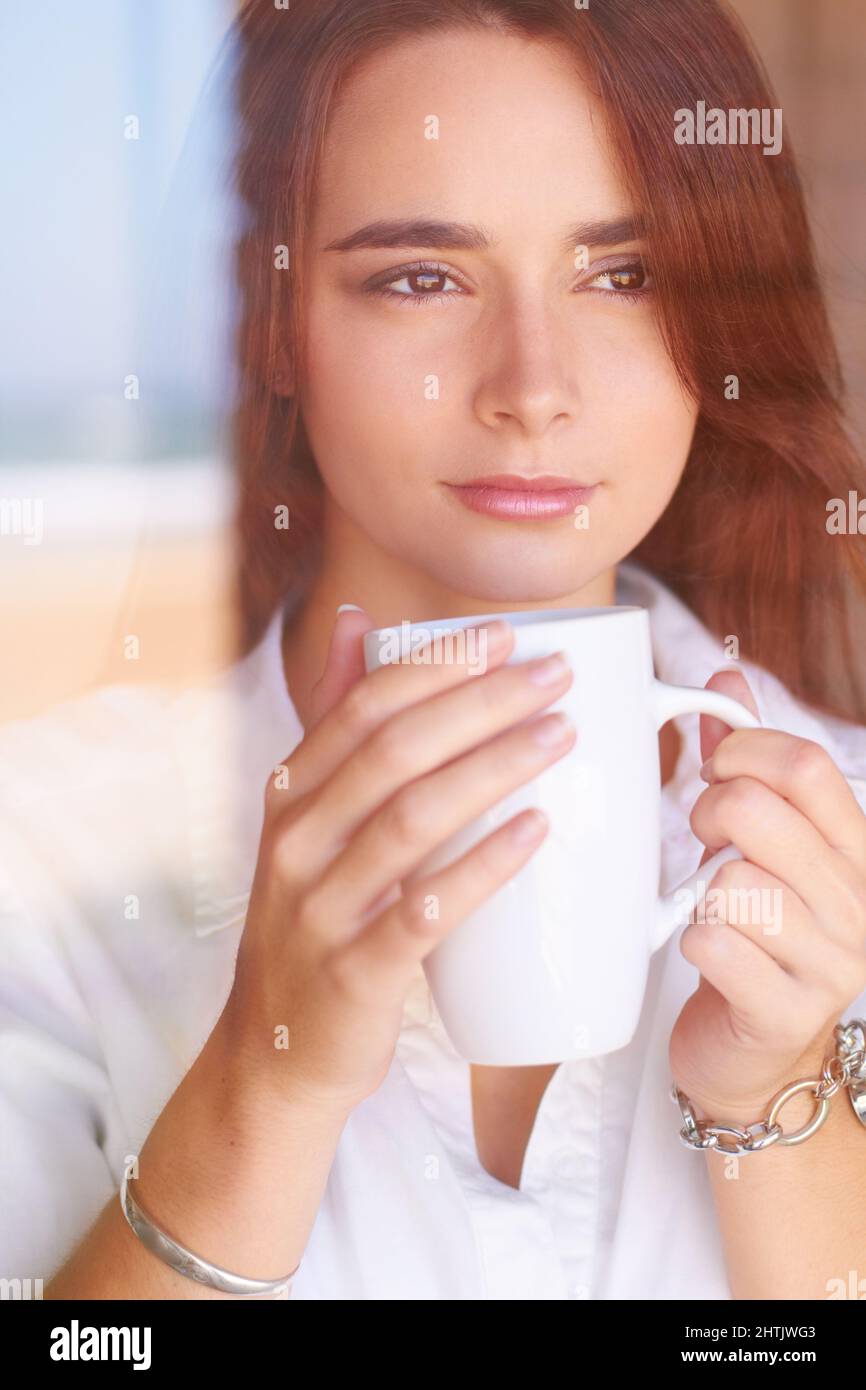 Coffee and contemplation. A young woman looking thoughtful while ...