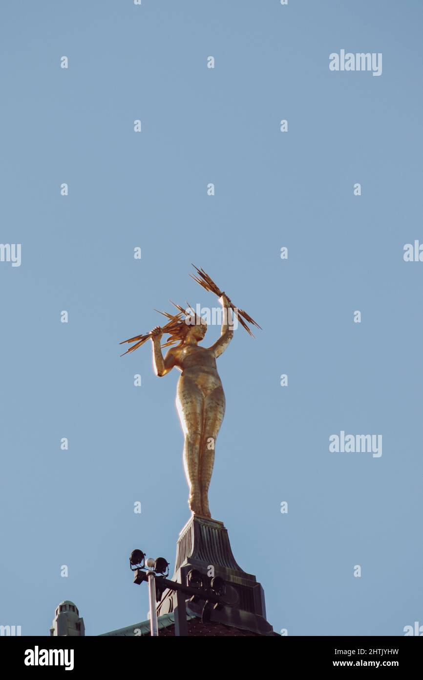 Statue in gold color on the top of the building Stock Photo - Alamy