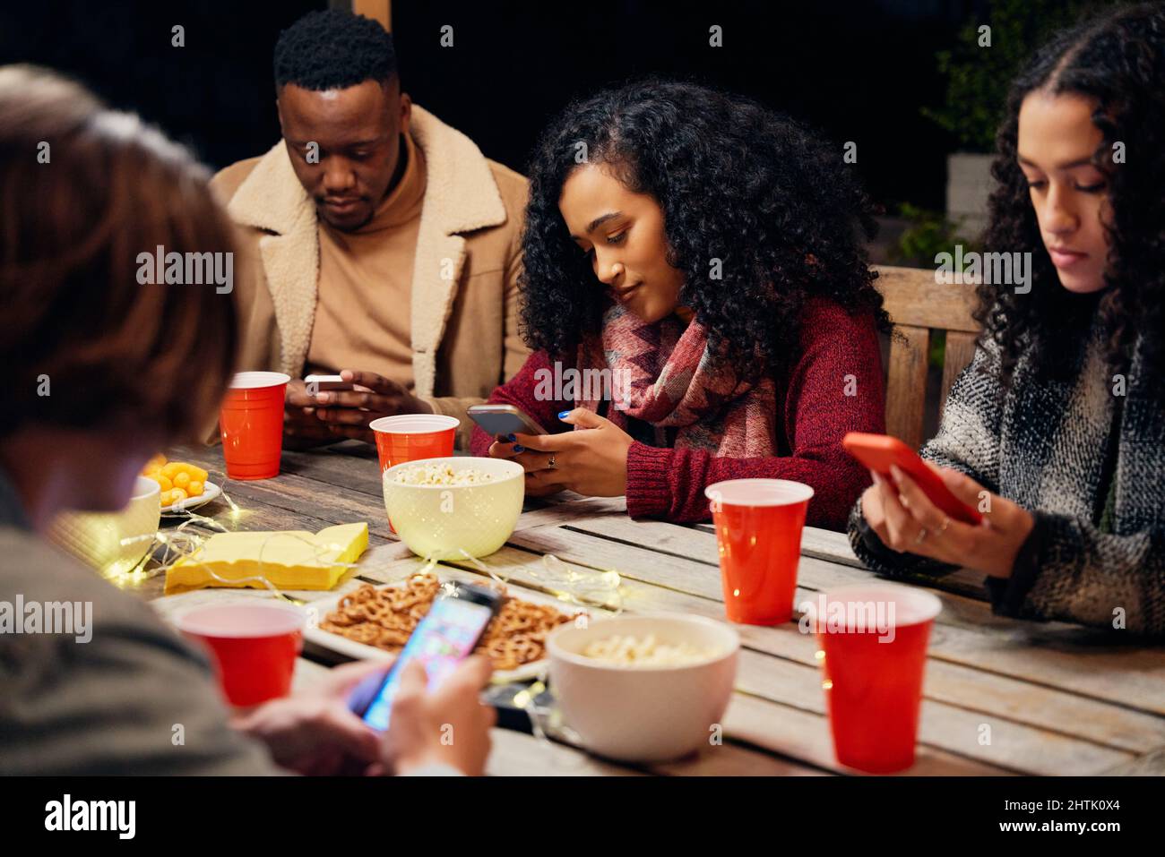 Group of diverse young adult friends sitting around table at party all ...