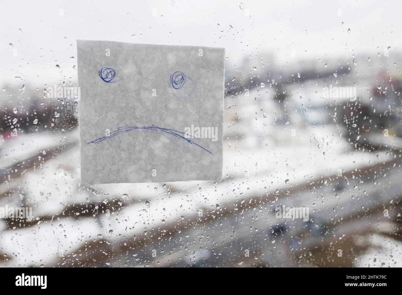 sad emoticon on a sticker glued on rainy window. depression and longing ...