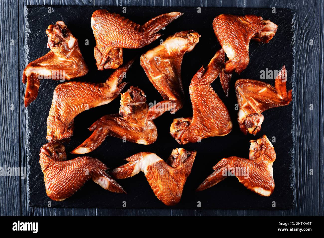 cold smoked chicken wings in a black stone plate on a wooden table ...
