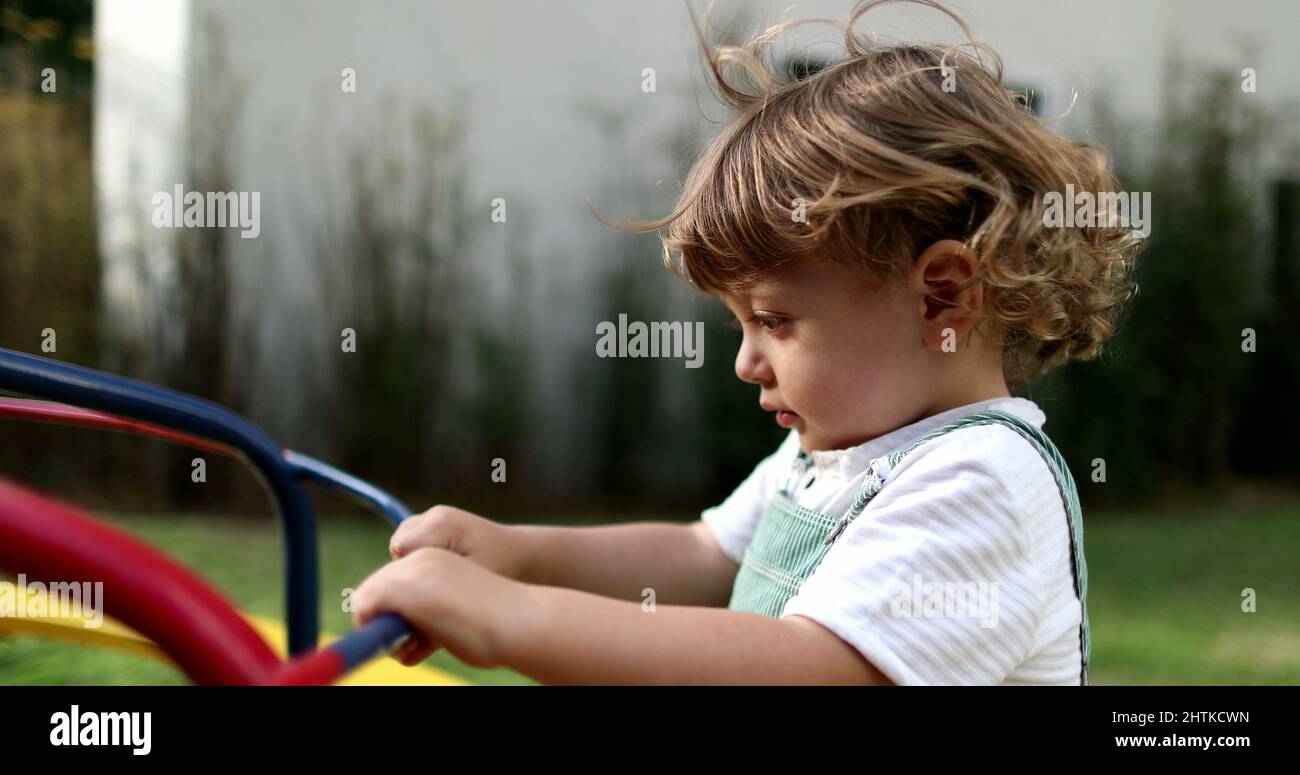 Cute baby toddler spinning on carousel at playground park Stock Photo ...