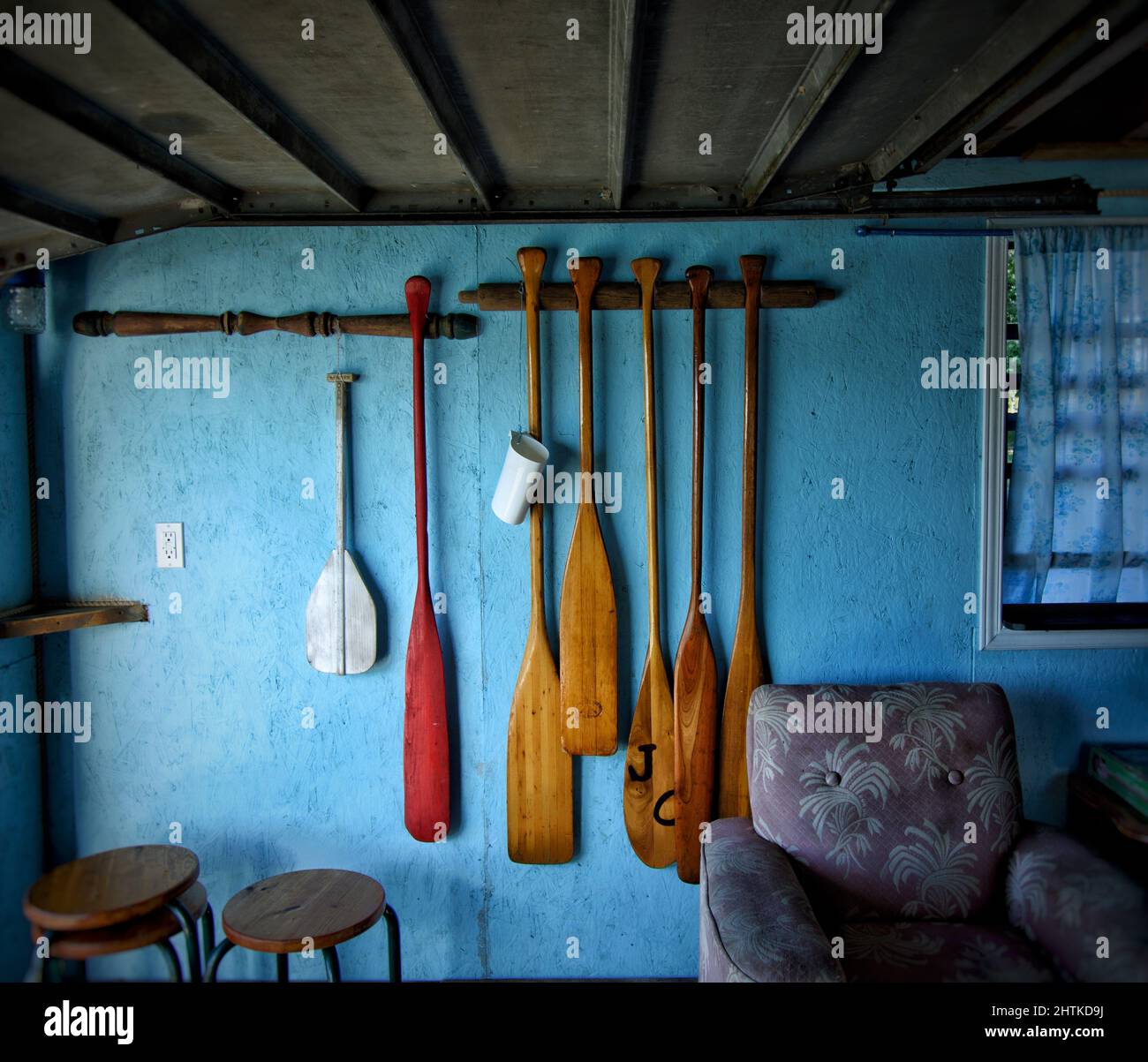 Interior of a blue boathouse with paddles hanging on the wall in ...