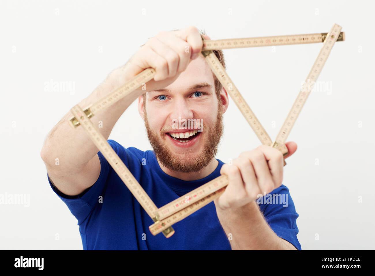 The measurements of a home. Portrait of a happy young man holding up a ...