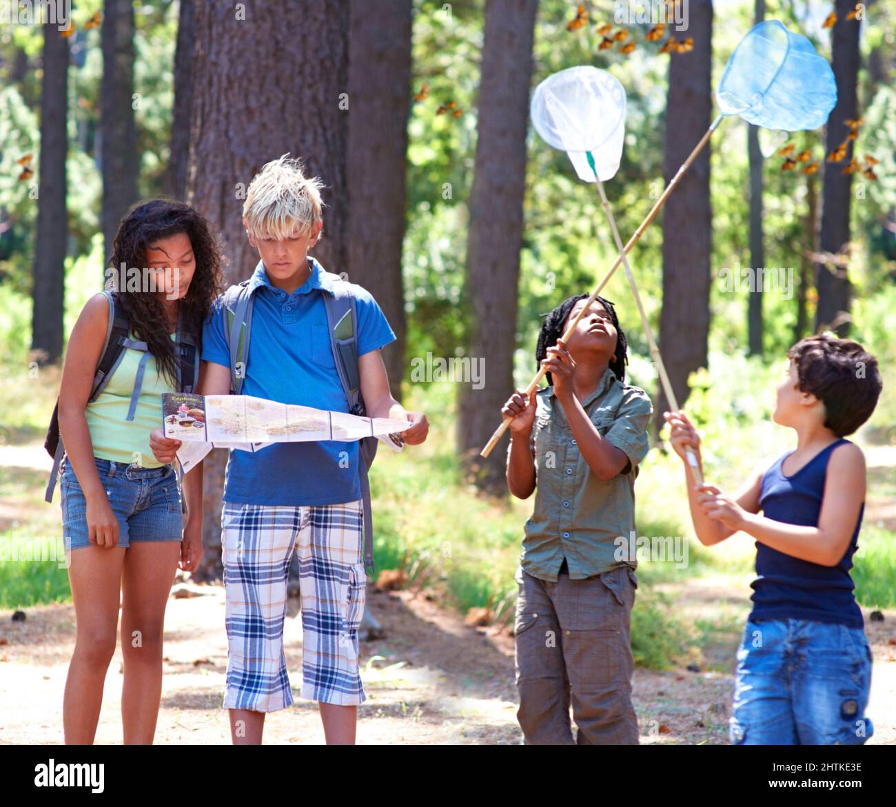 An outdoor experience. Multi-ethnic kids exploring a map while standing ...