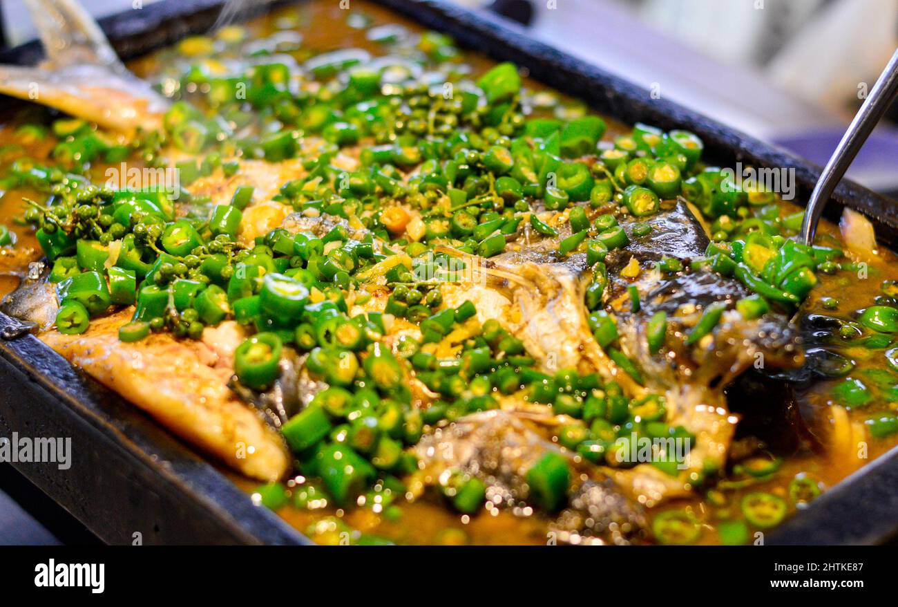 China Hunan local fish hot pot topped with green chilies and pepper ...