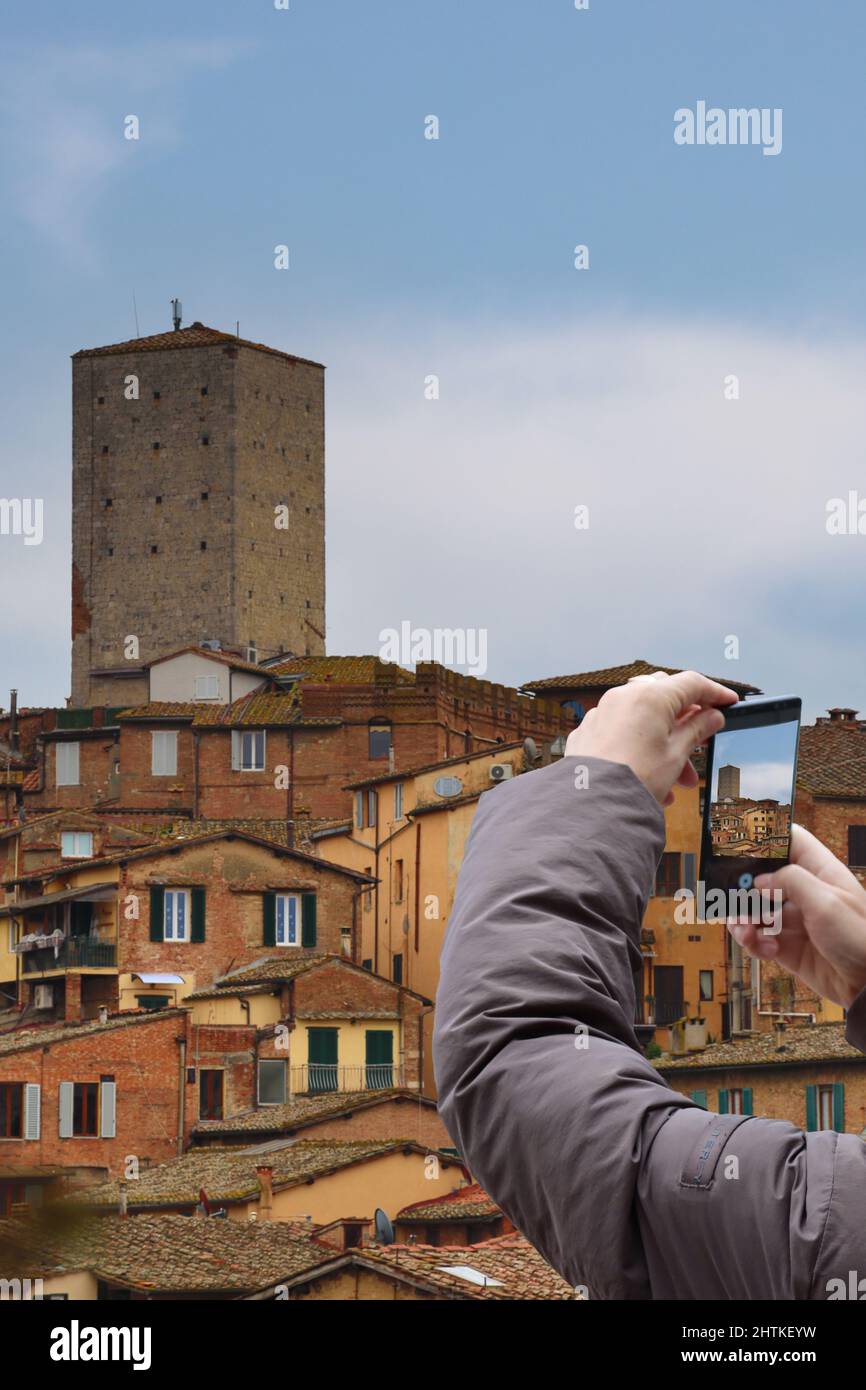 Closeup of a person with mobile phone photographing panorama of Siena ...