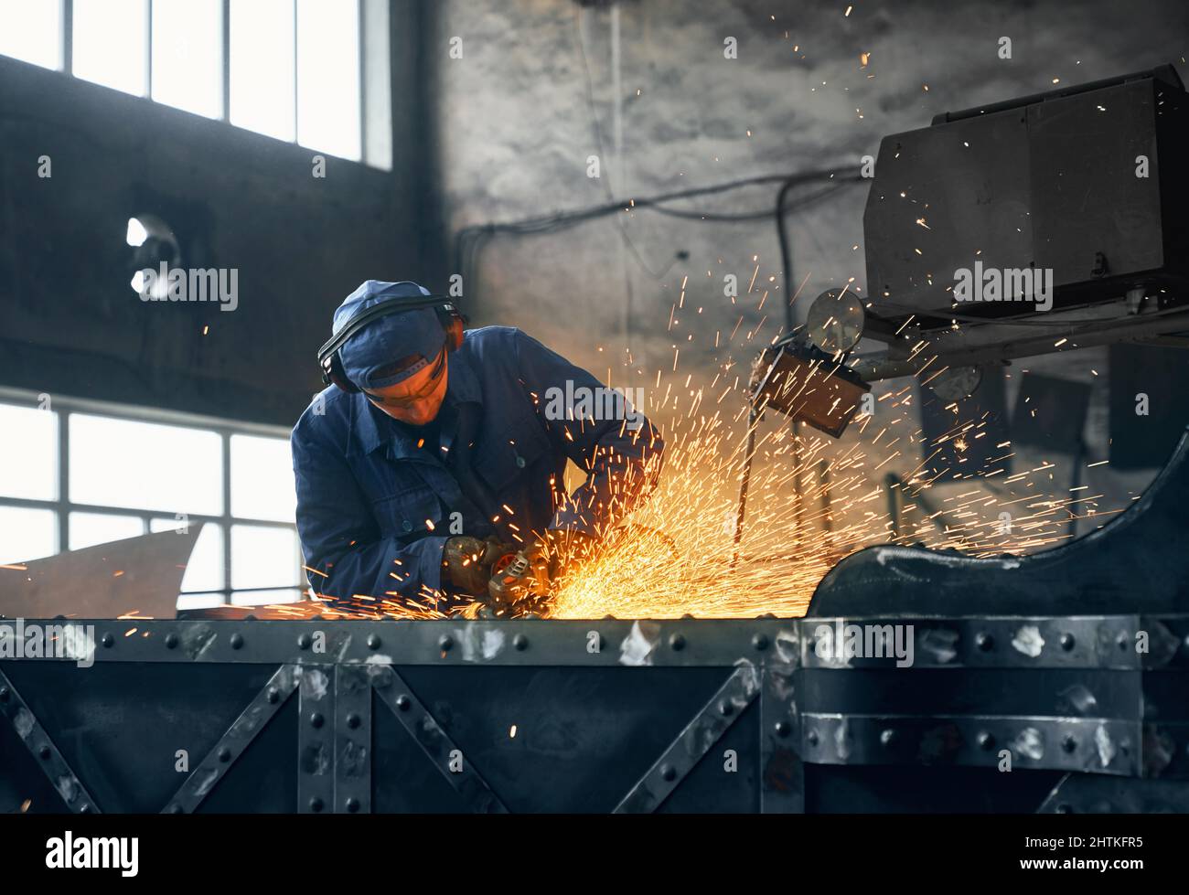 Professional craftsman making flying sparks while processing with metal ...
