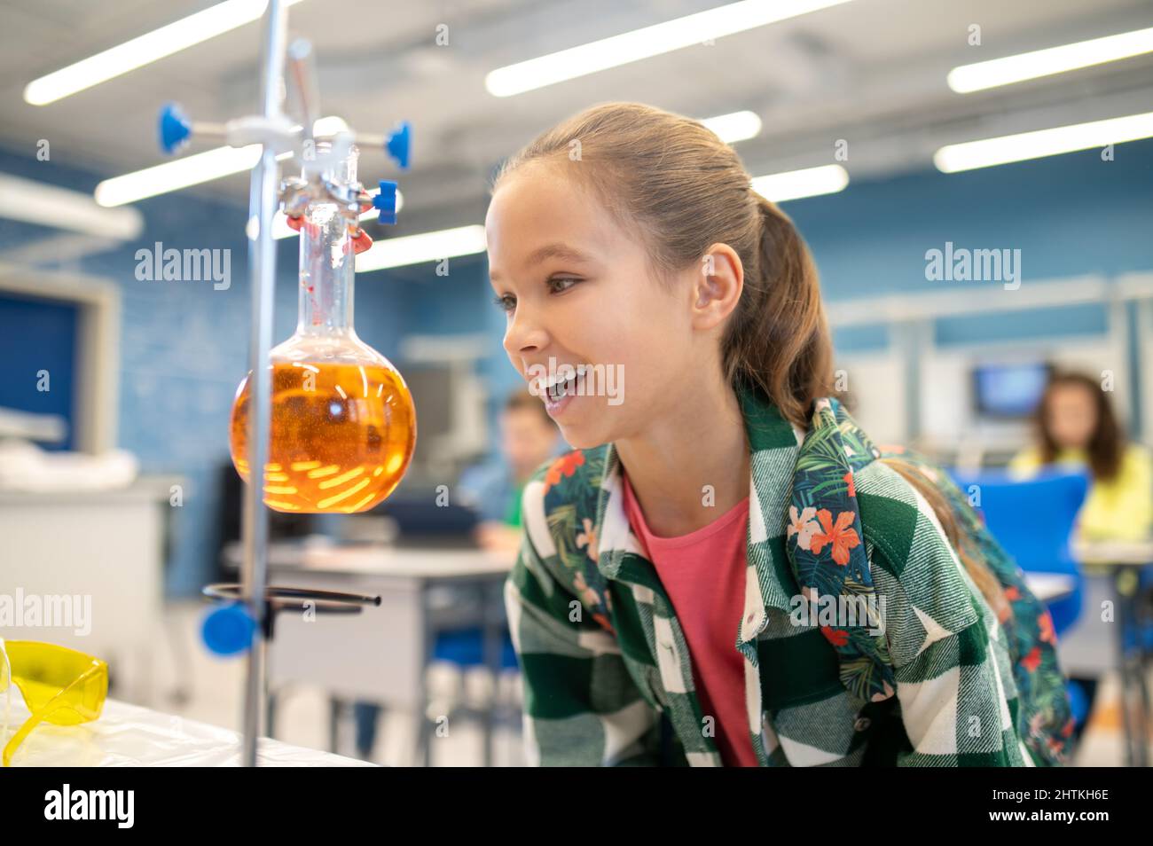 Girl with delight looking at flask in chemistry class Stock Photo - Alamy