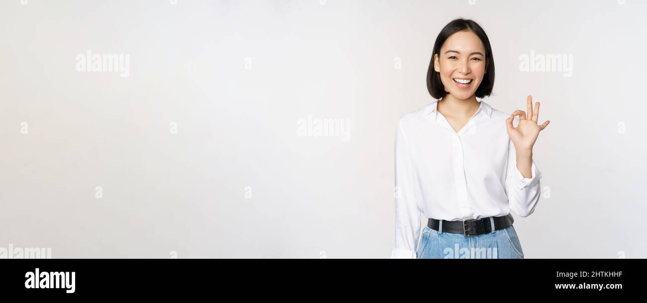 Very good. Smiling asian woman showing okay with satisfied face ...