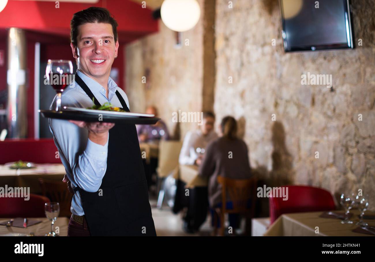 waiter with serving tray welcoming to restaurant Stock Photo - Alamy