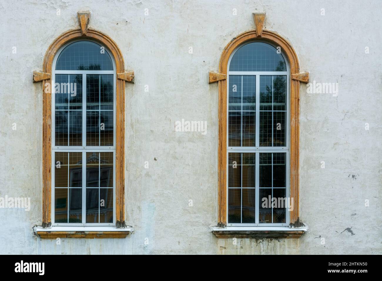 Two old arched windows on the background of an old gray wall. From the ...