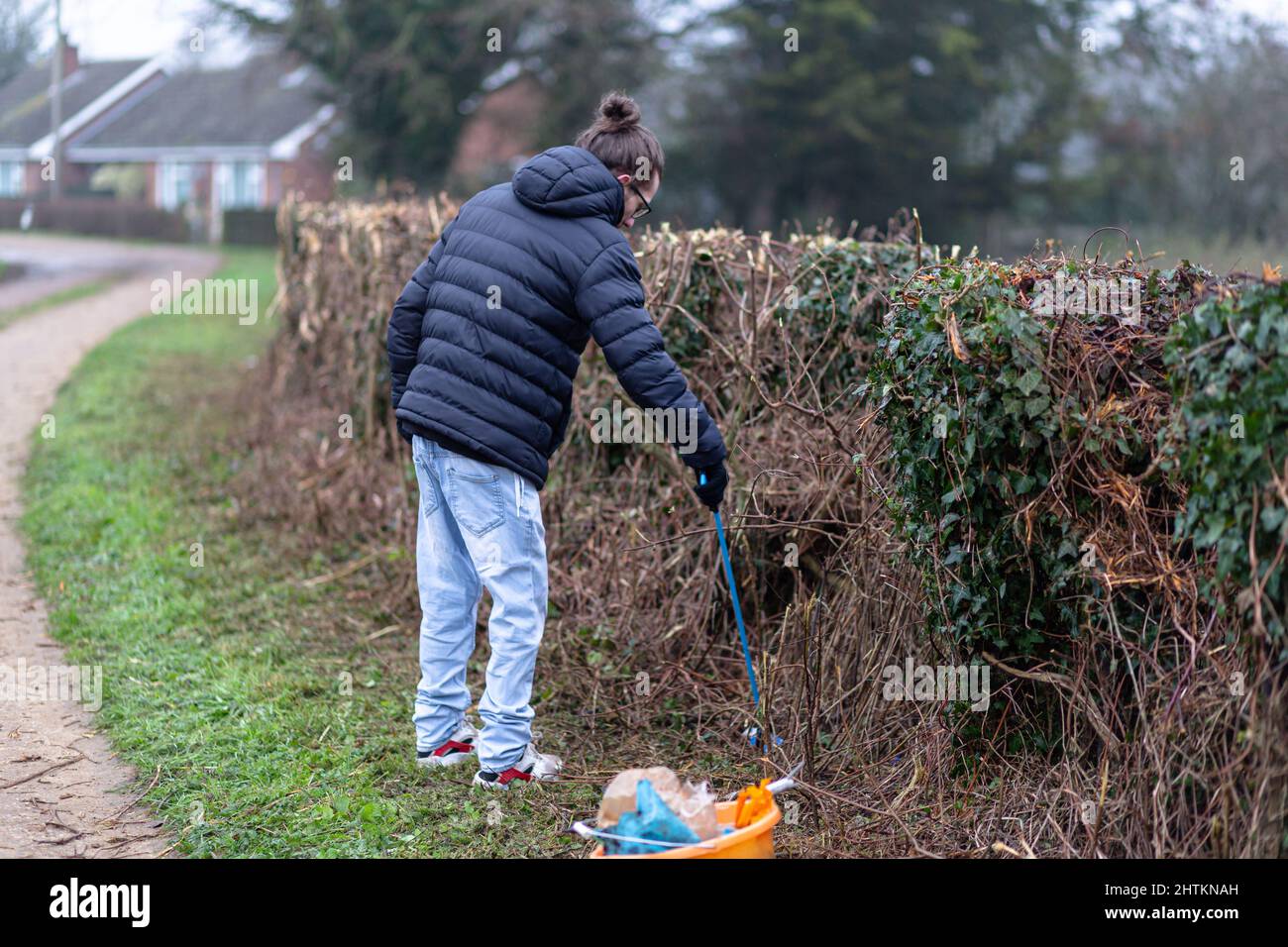 A young man with a litter picker and a bucket collecting litter and ...