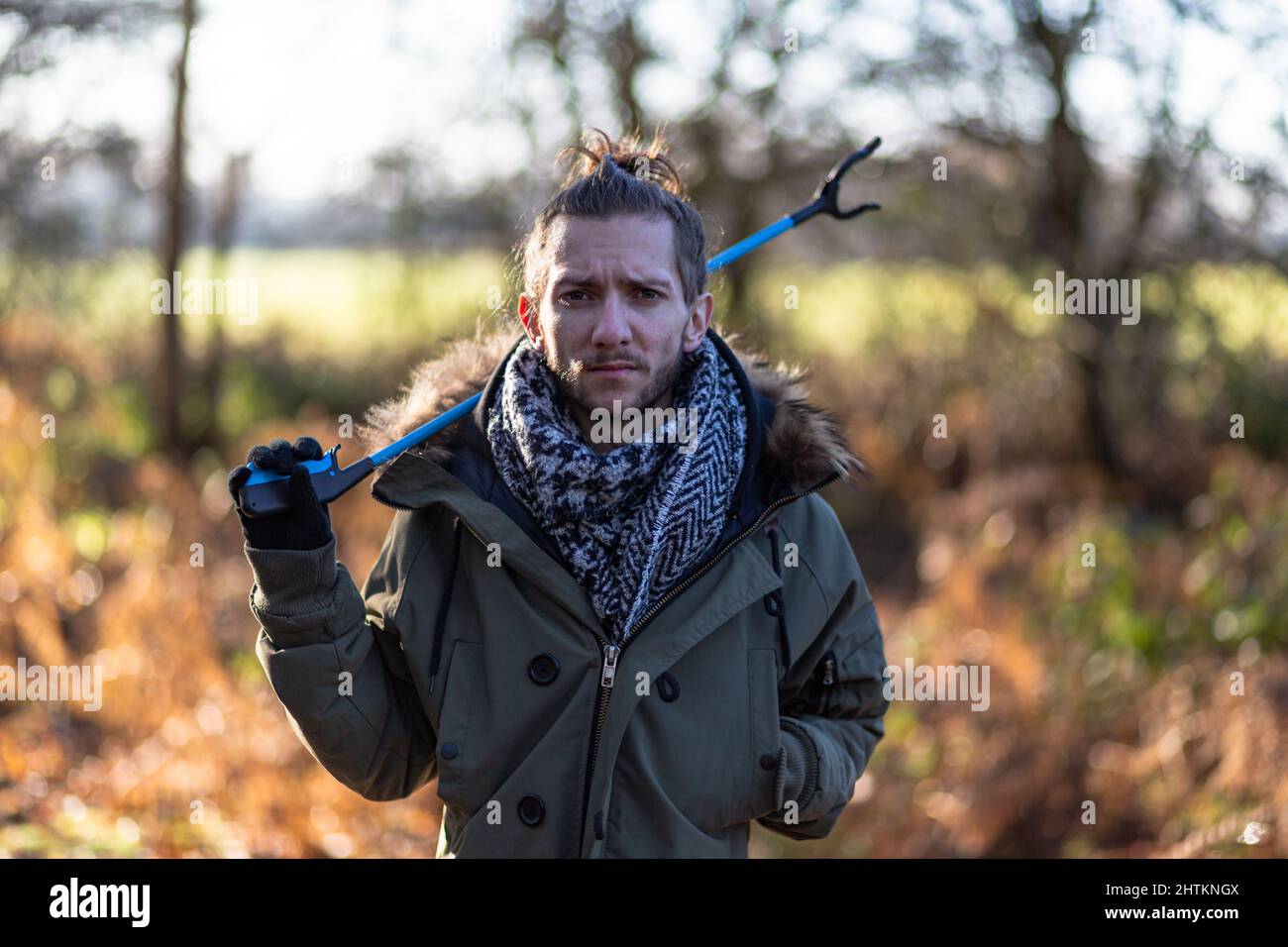 A portrait of a young bearded man with a litter picker ready to do a ...