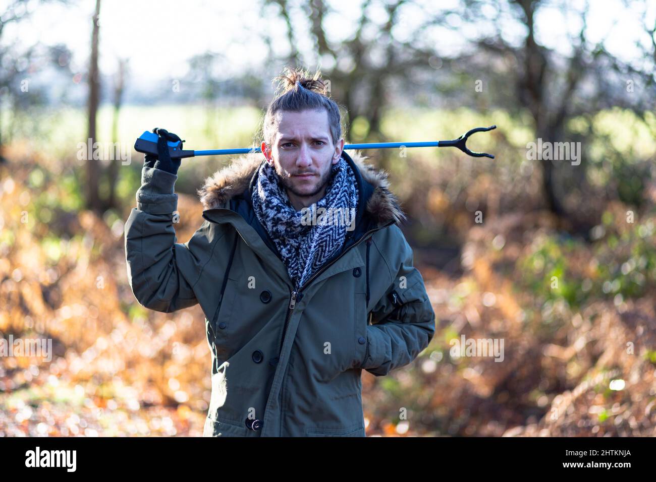 A portrait of a young bearded man with a litter picker ready to do a ...