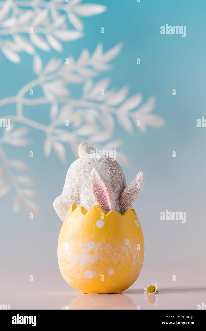 A white rabbit hid in an Easter egg on a blue background. Festive ...