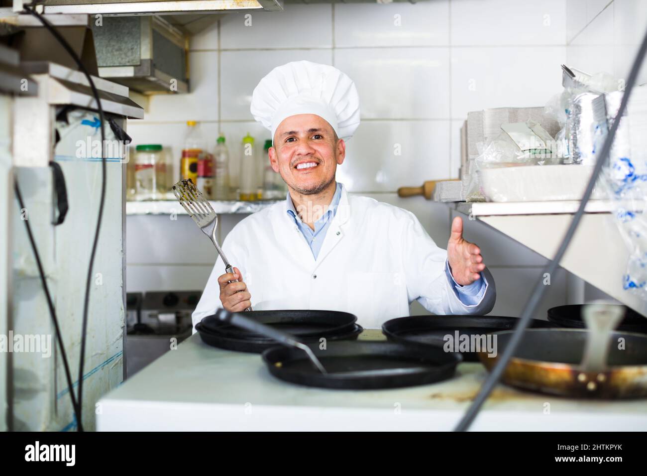 mature chef with frying pans in kitchen Stock Photo - Alamy