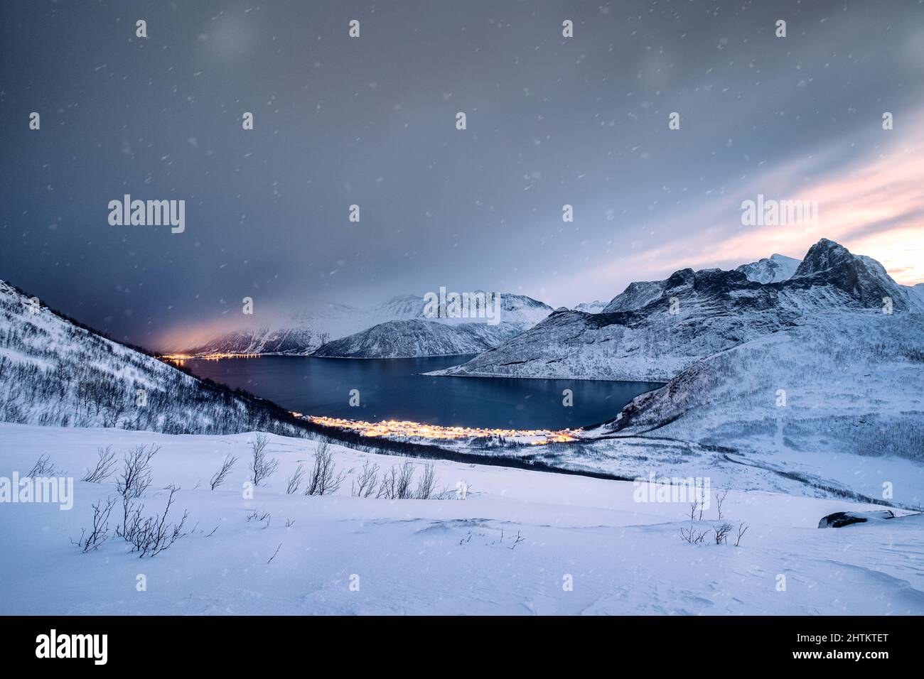 Scenery of snow covered mountain range with illuminated town on ...