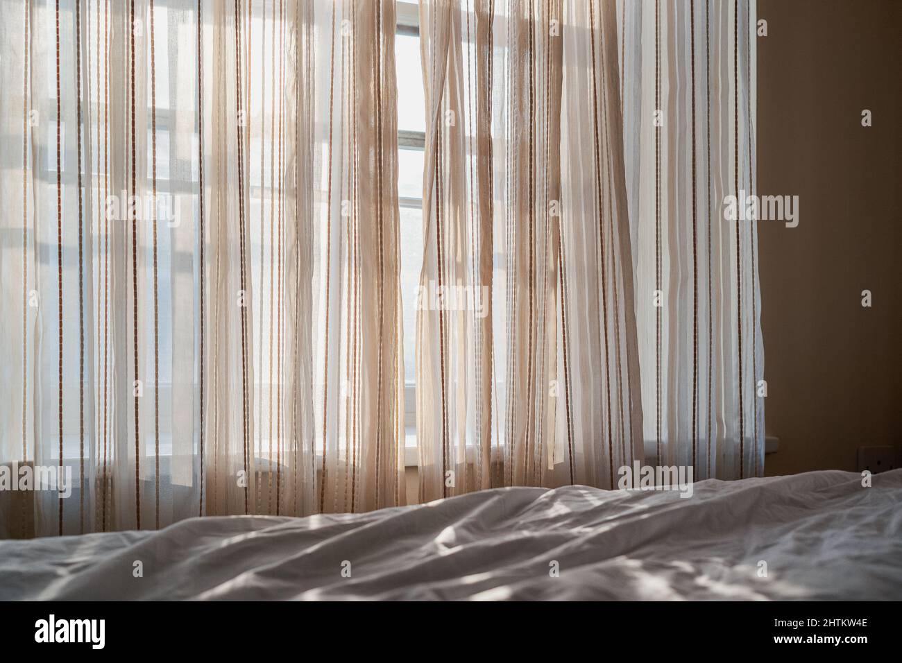 Light linen style textured curtains letting morning sunlight into a ...