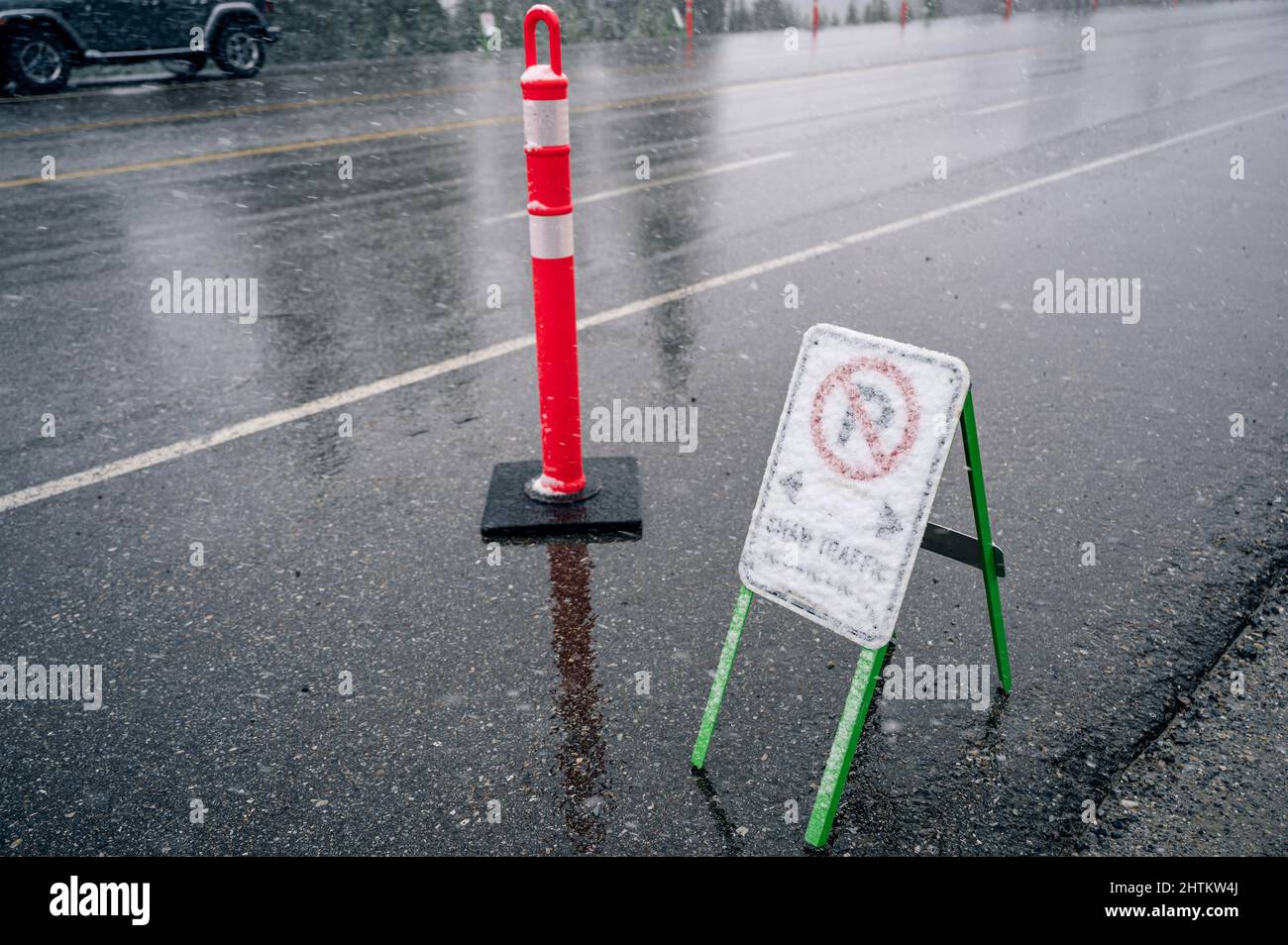 No parking sign and warning post on asphalt road in snow storm due road ...