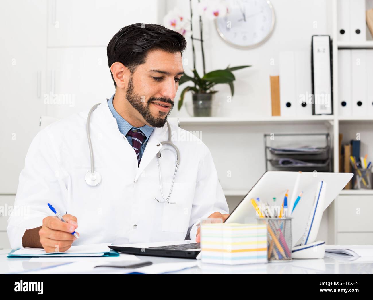 Spanish man doctor is working with documents behind laptop Stock Photo ...