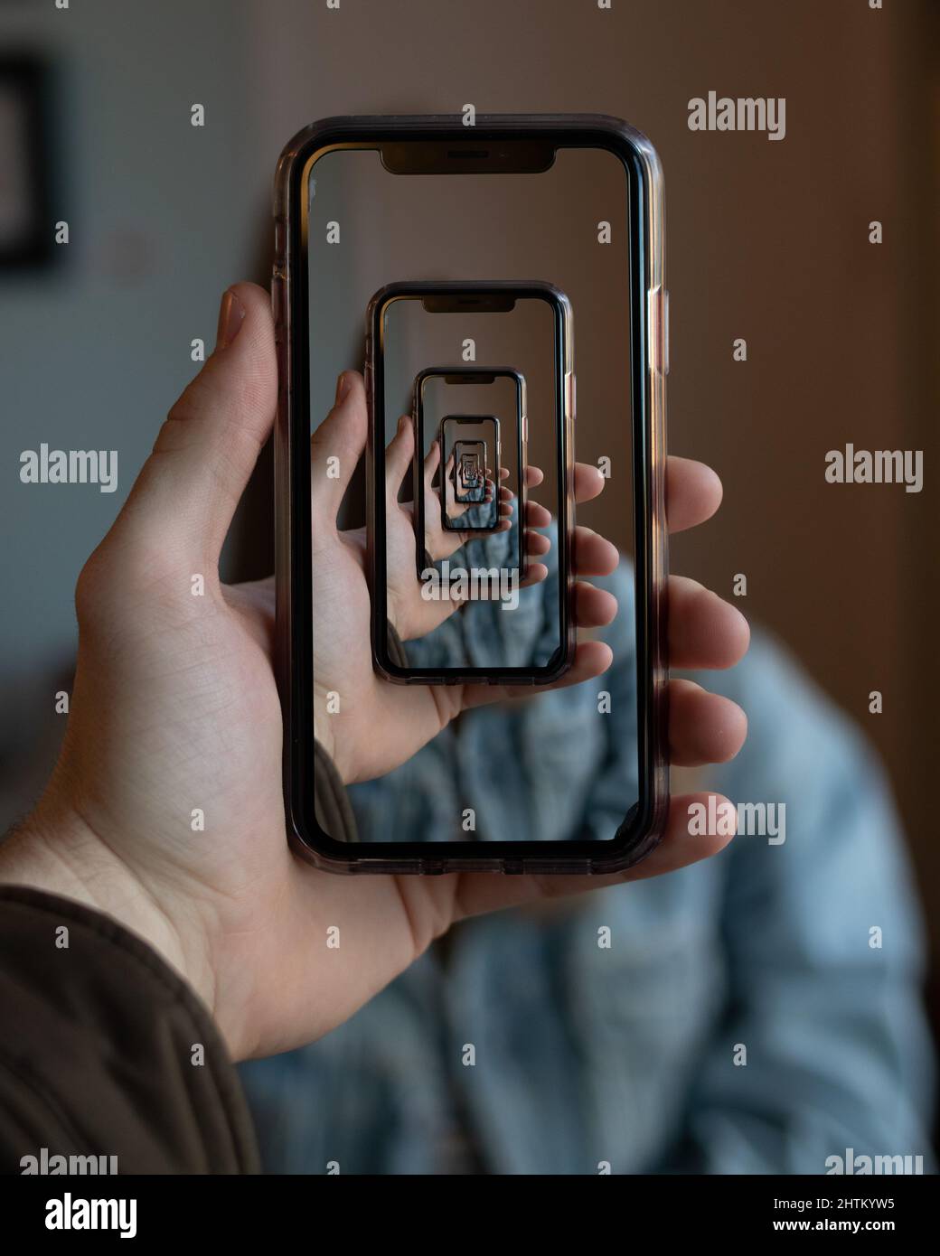 A person holding a phone with many trippy mirroring repetitions of the ...