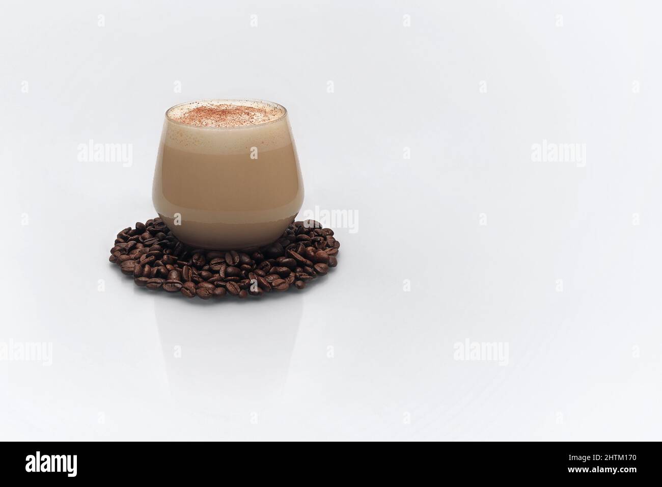 A cup of coffee sprinkled with powder on a trivet made of coffee beans ...