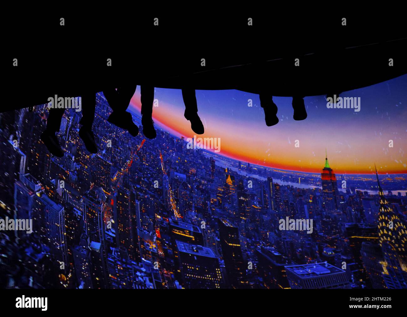 The legs of riders dangle off of a flying theater ride that pitches ...