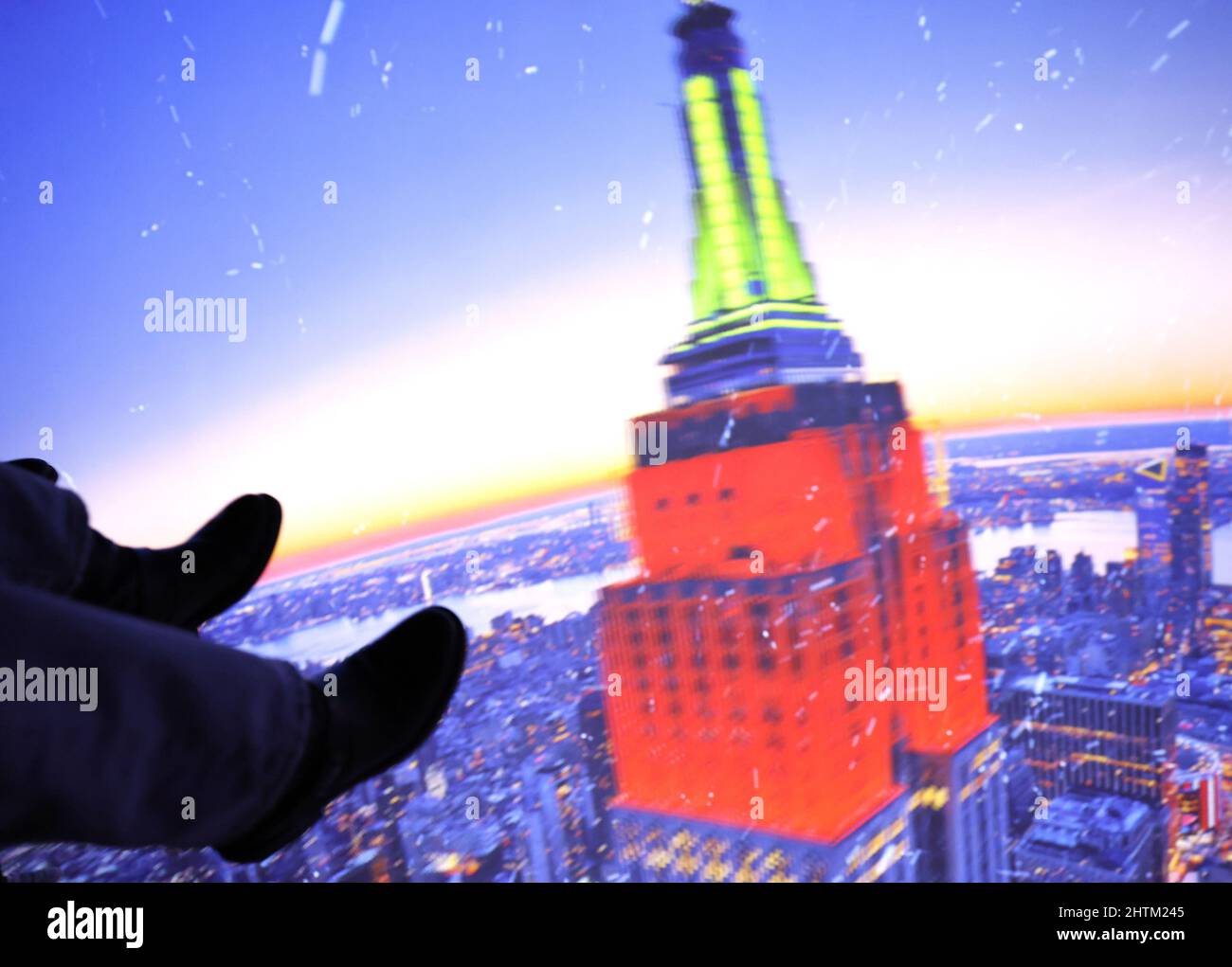 The legs of riders dangle off of a flying theater ride that pitches ...