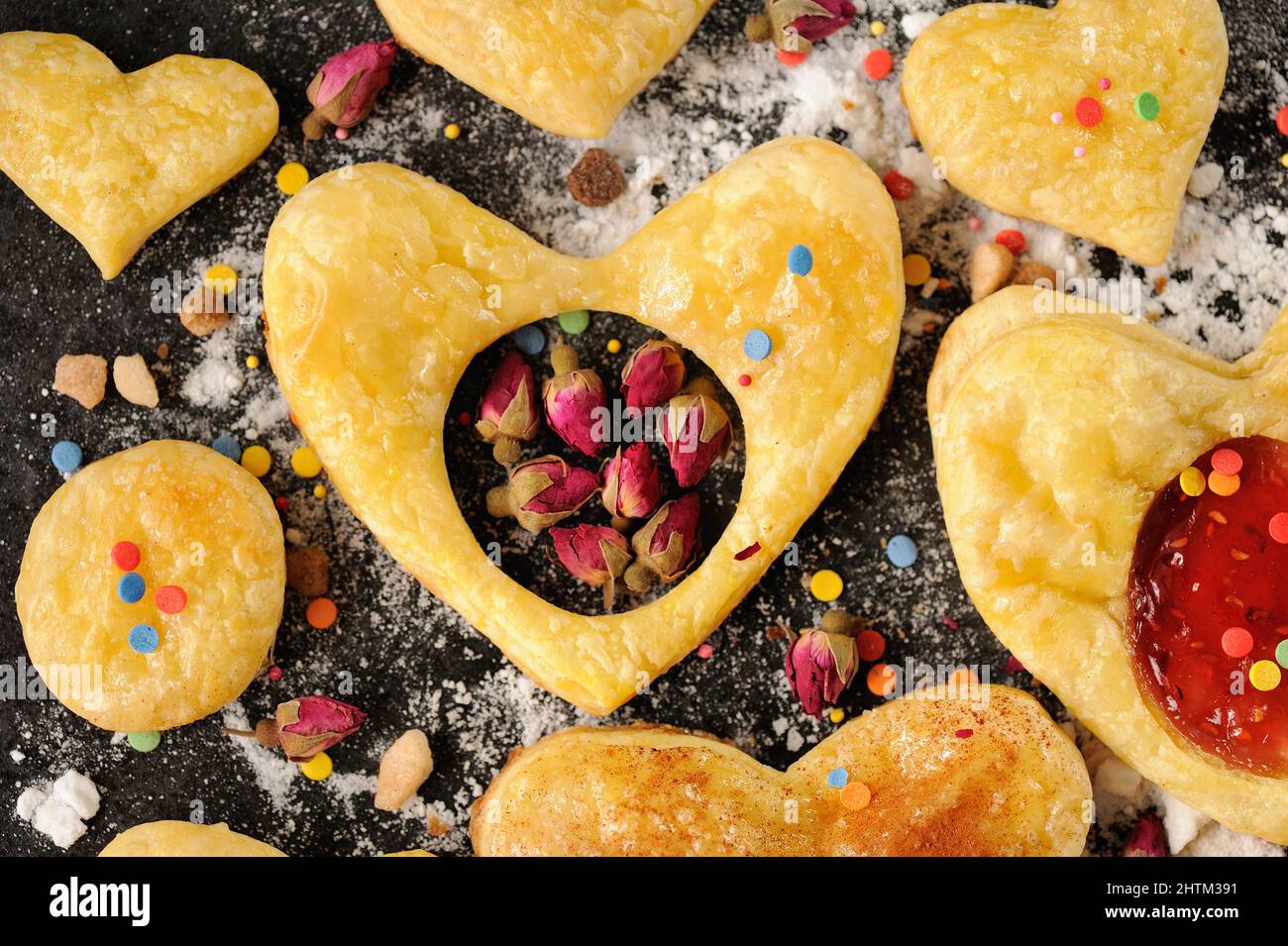 Homemade puff pastry hearts decorated with rose buds and icing sugar on ...