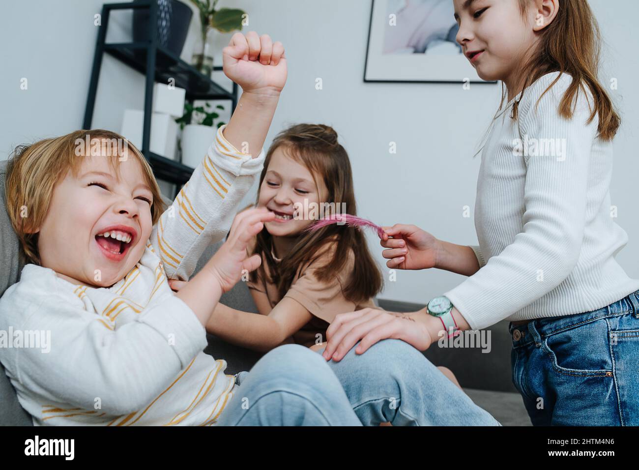 Team of girls ganging up to tickle a boy. One with hands, other with ...