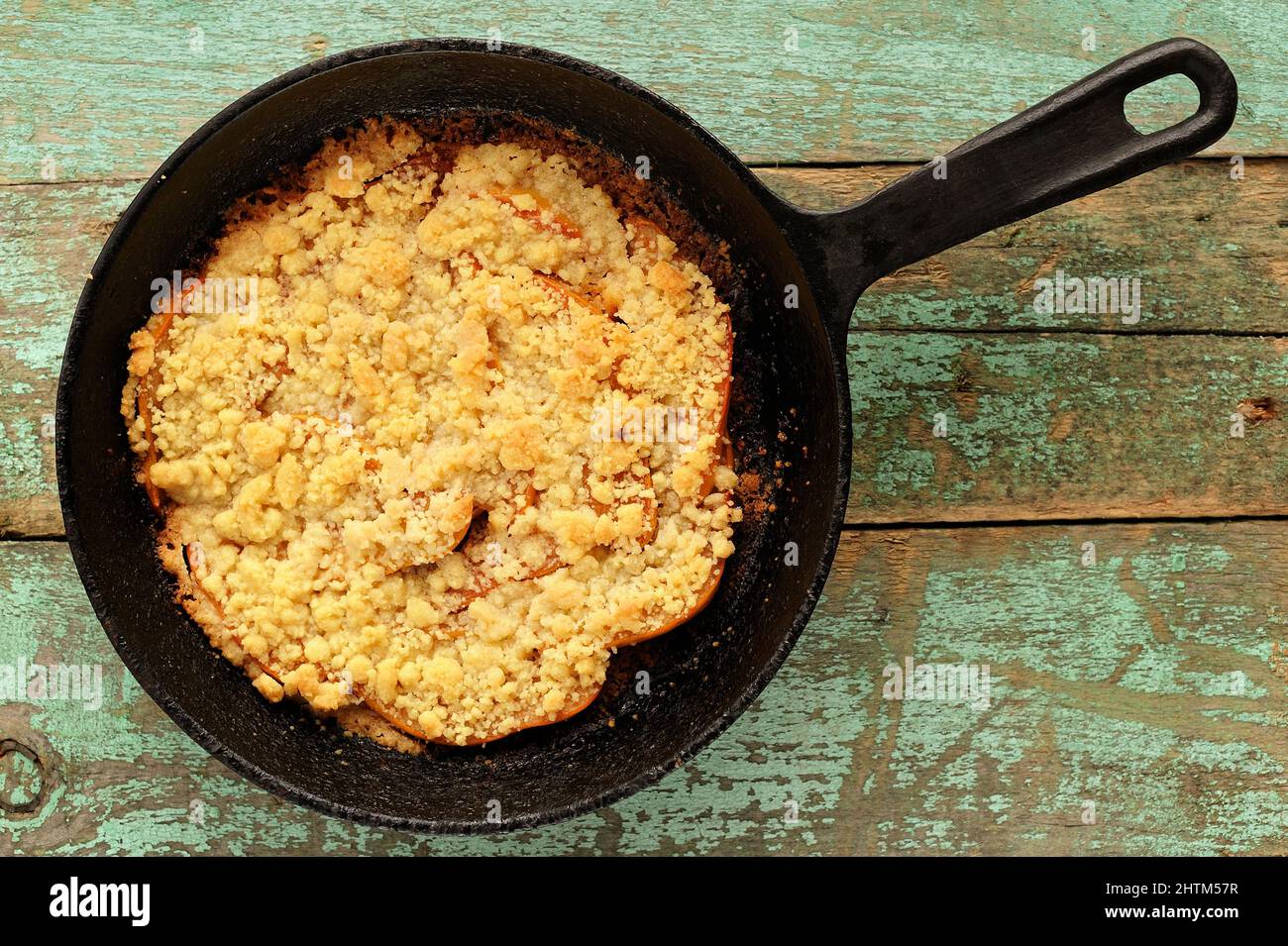 Homemade tasty quince crumble pie in black cast iron pan overhead view ...